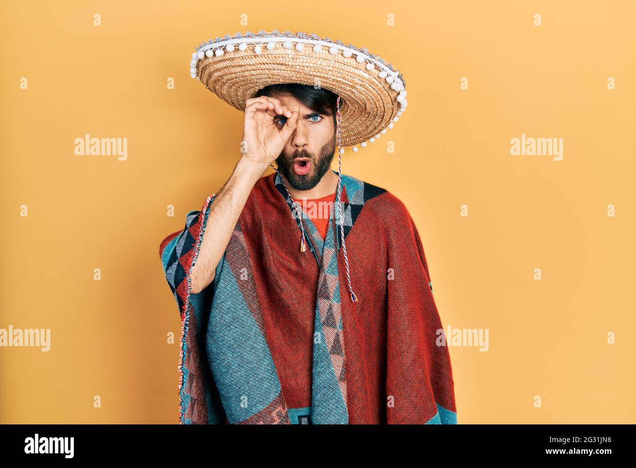 Young hispanic man holding mexican hat doing ok gesture shocked with ...