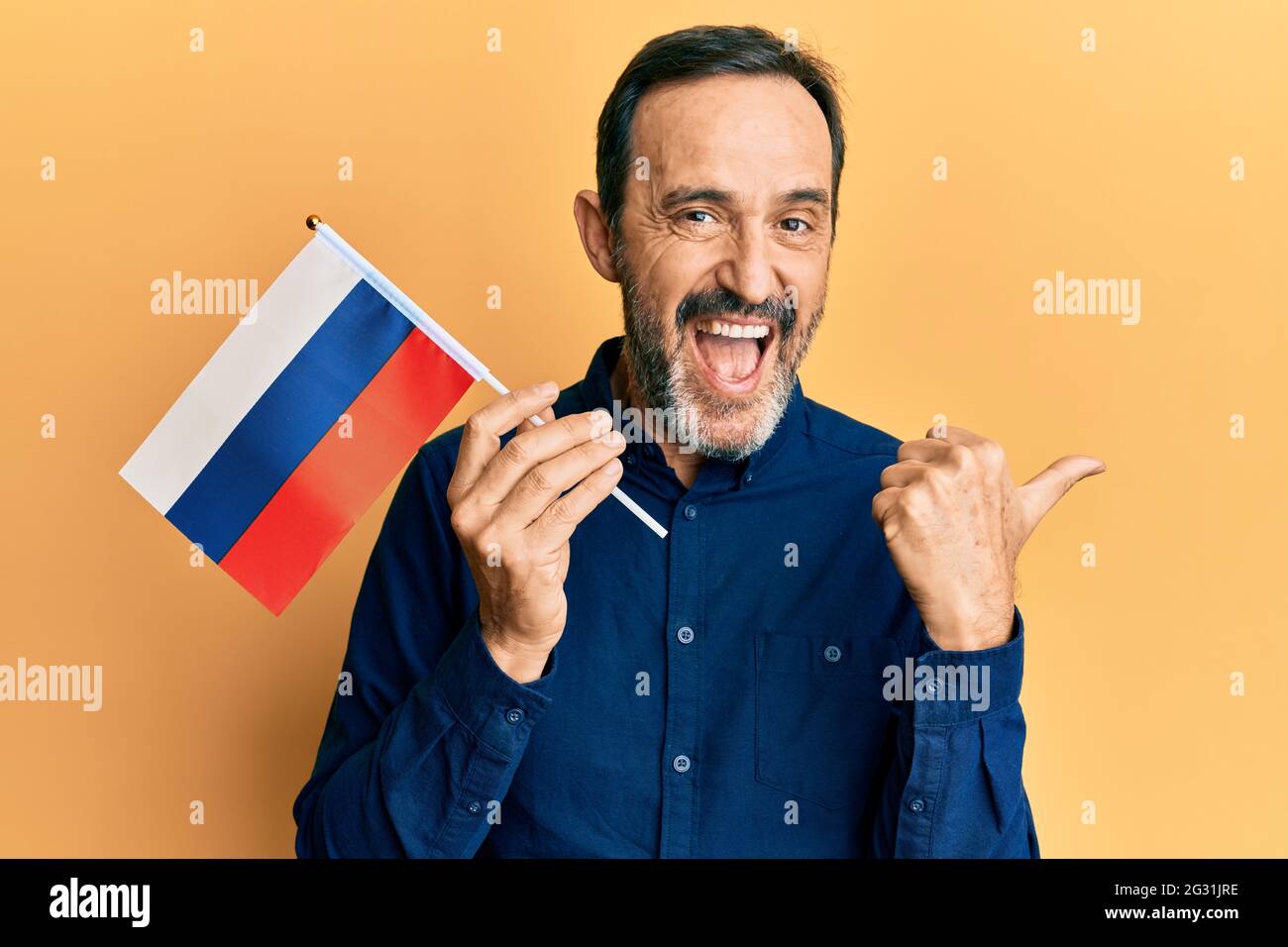 Middle age hispanic man holding russia flag pointing thumb up to the ...
