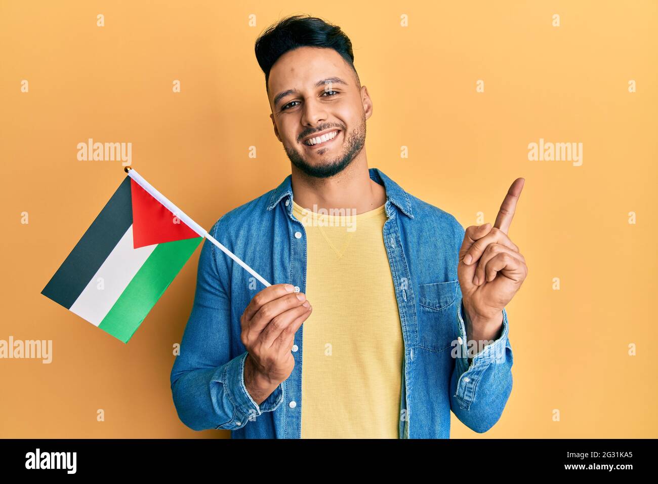 Young arab man holding palestine flag smiling happy pointing with hand ...