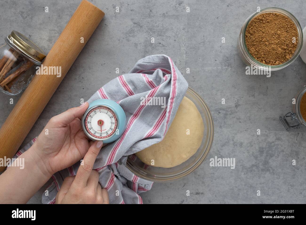 Woman hands pointing to an analog timer to control cinnamon roll dough ...