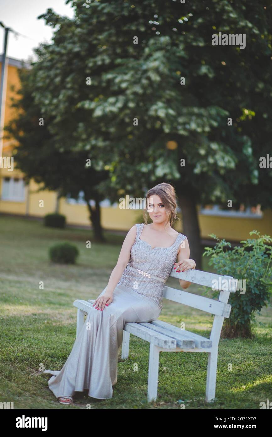 An attractive Caucasian female wearing an elegant long silver dress ...