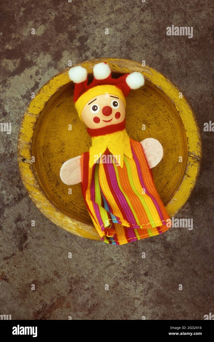 Old yellow wooden dish containing puppet or doll with round wooden head ...