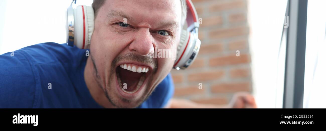 Man with headphones sitting at computer screen and screaming with joy ...