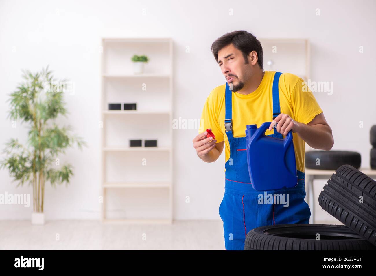Young garage worker with tyre at workshop Stock Photo - Alamy