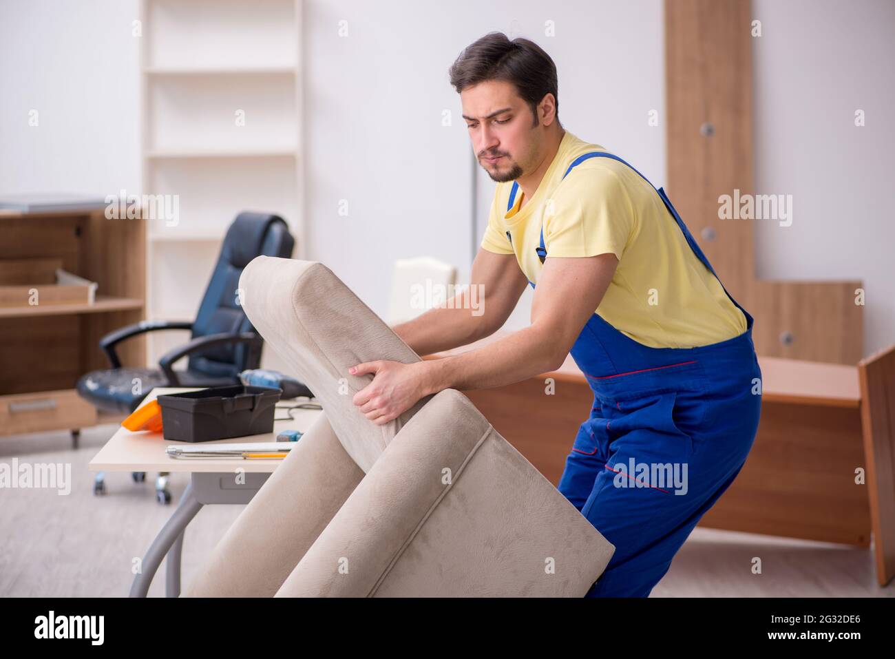 Young carpenter repairing arm-chair in the office Stock Photo - Alamy