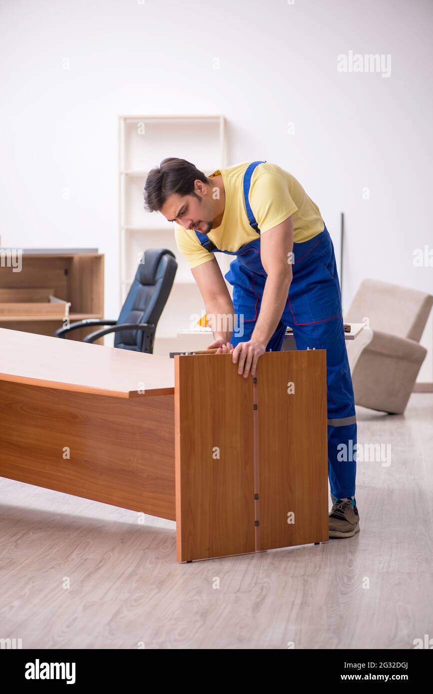 Young carpenter repairing desk in the office Stock Photo - Alamy
