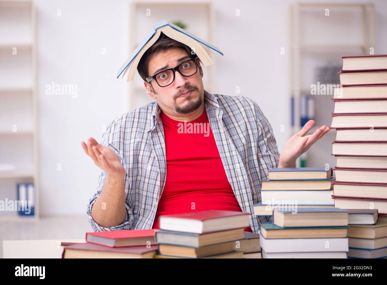 Young student and too many books in the classroom Stock Photo - Alamy