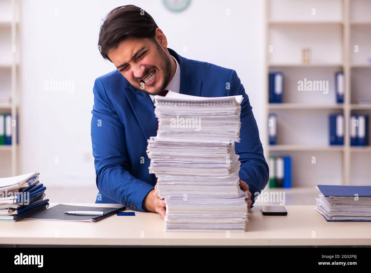 Young male employee and too much work in the office Stock Photo - Alamy