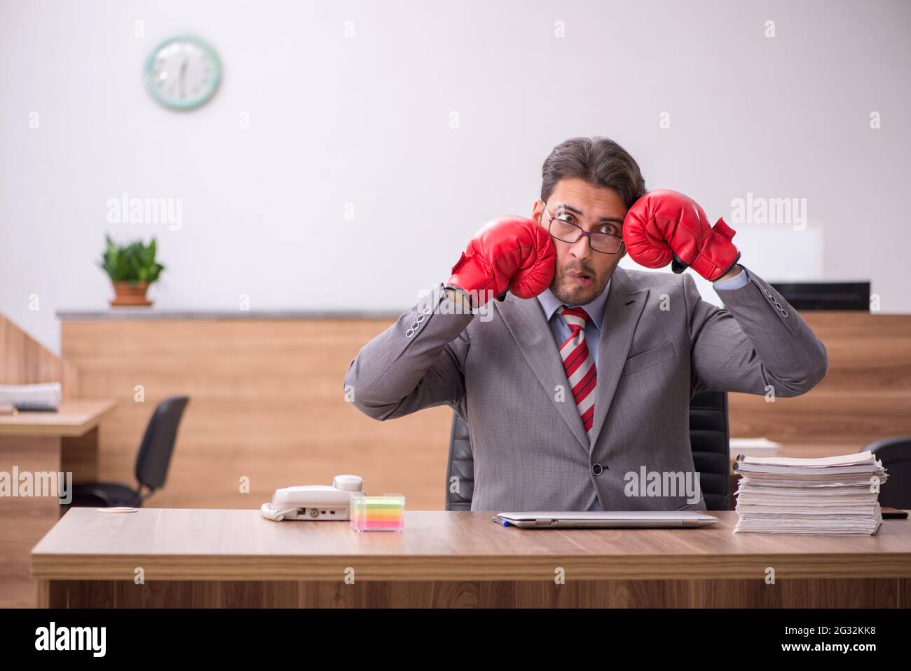Young businessman employee wearing boxing gloves at workplace Stock ...
