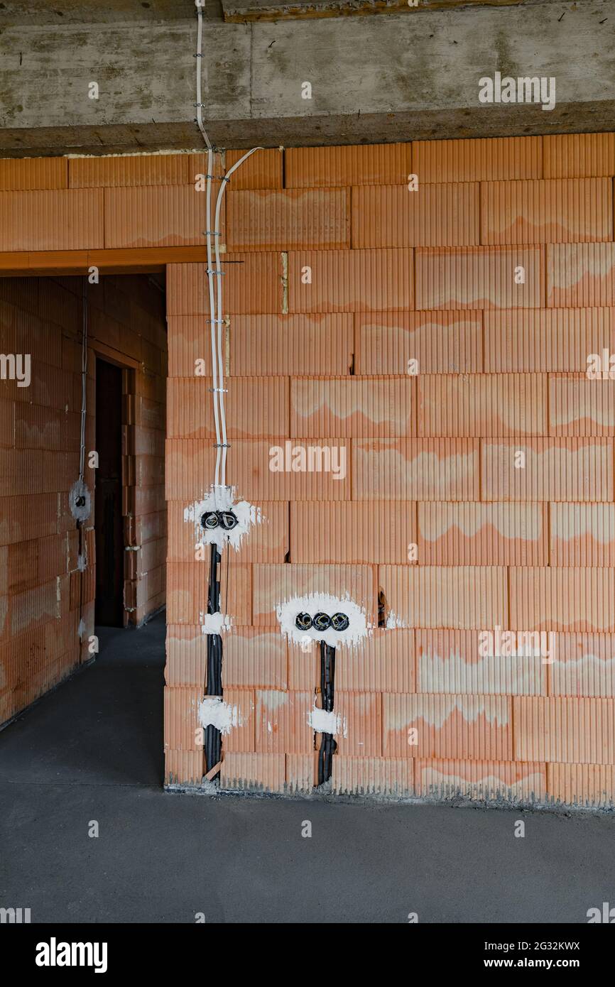 A vertical shot of a newly built red brick wall with sockets during ...