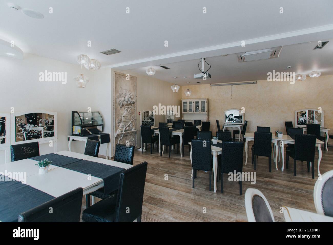 A restaurant empty room decor with tables and chairs in white and black ...