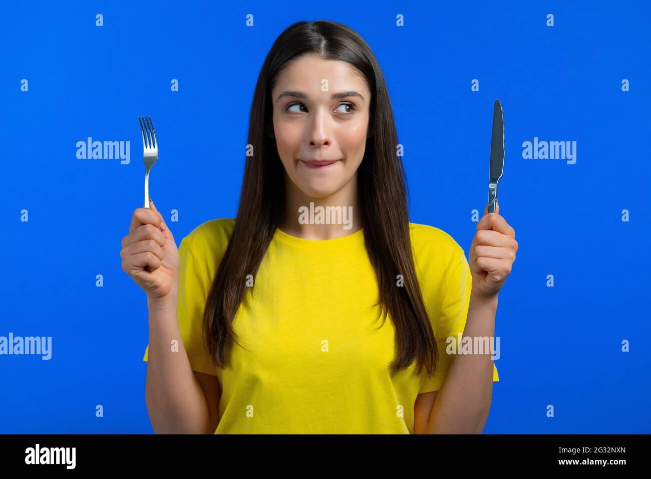 Portrait of hungry woman with fork and knife. Lady with anticipation ...