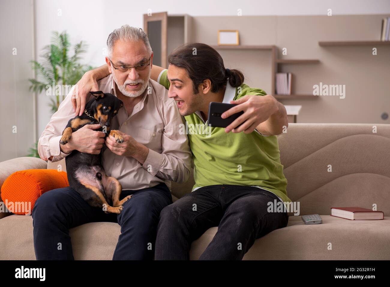 Two men with dog in the room Stock Photo - Alamy