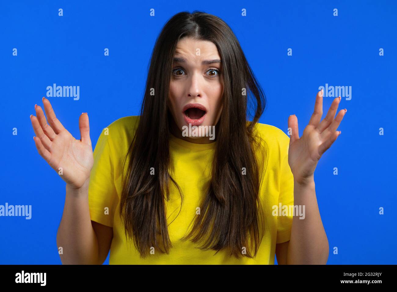 Portrait of unpleasantly surprised and shocked girl on blue studio ...