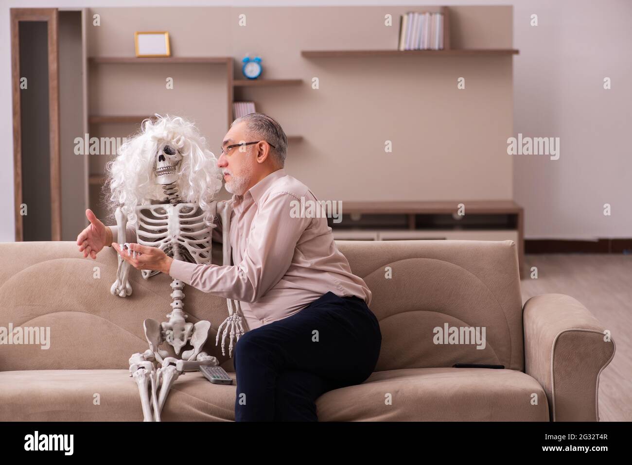 Old man sitting on the sofa with the female skeleton in undying love ...