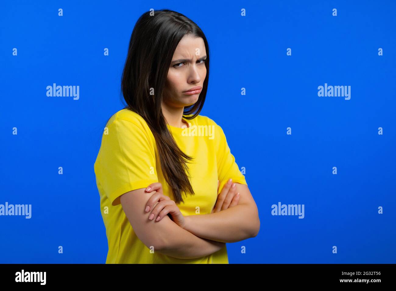 Angry offended woman keeping arms crossed and staring at camera with ...