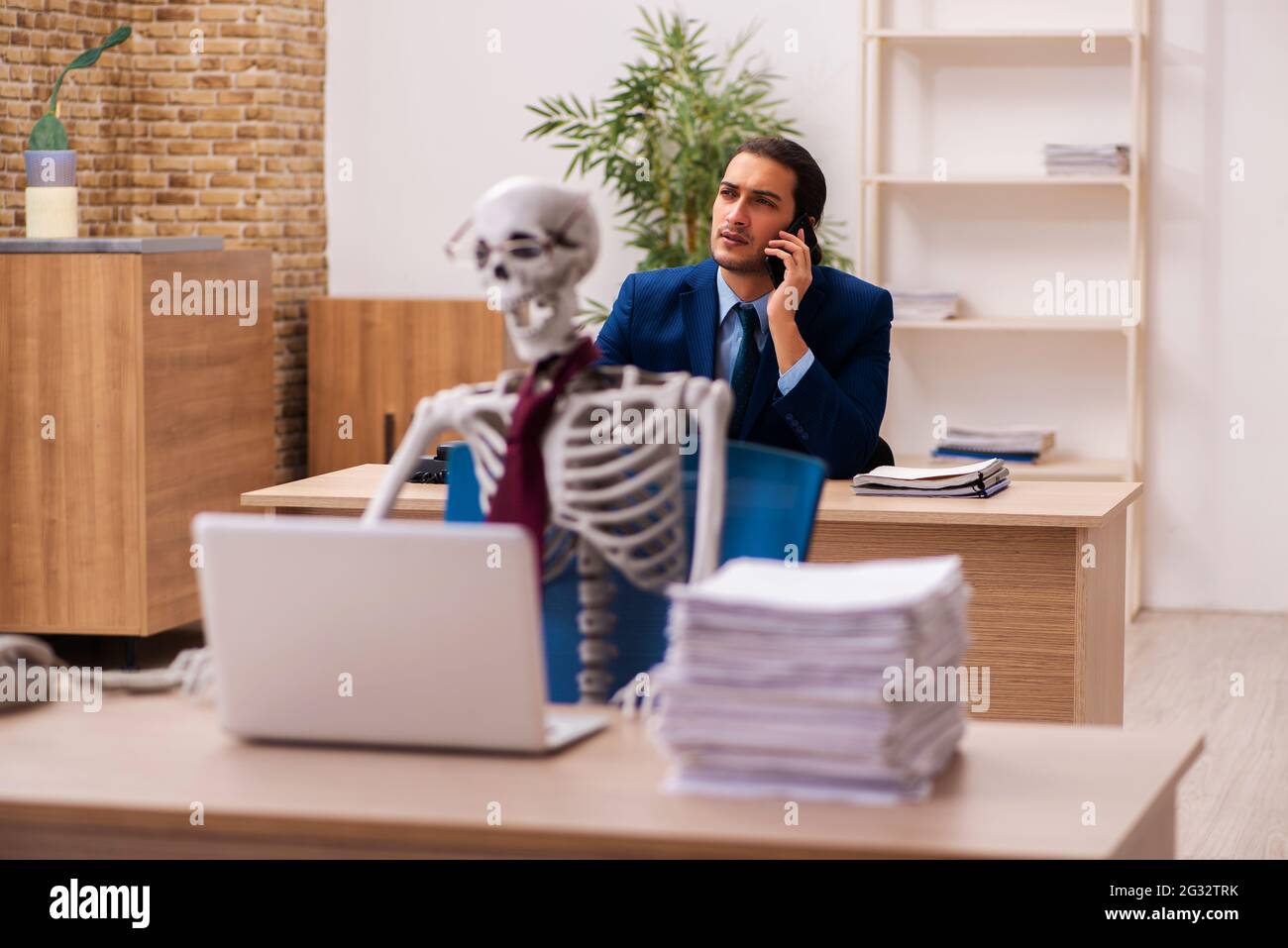 Dead employee working in the office in funny concept Stock Photo - Alamy