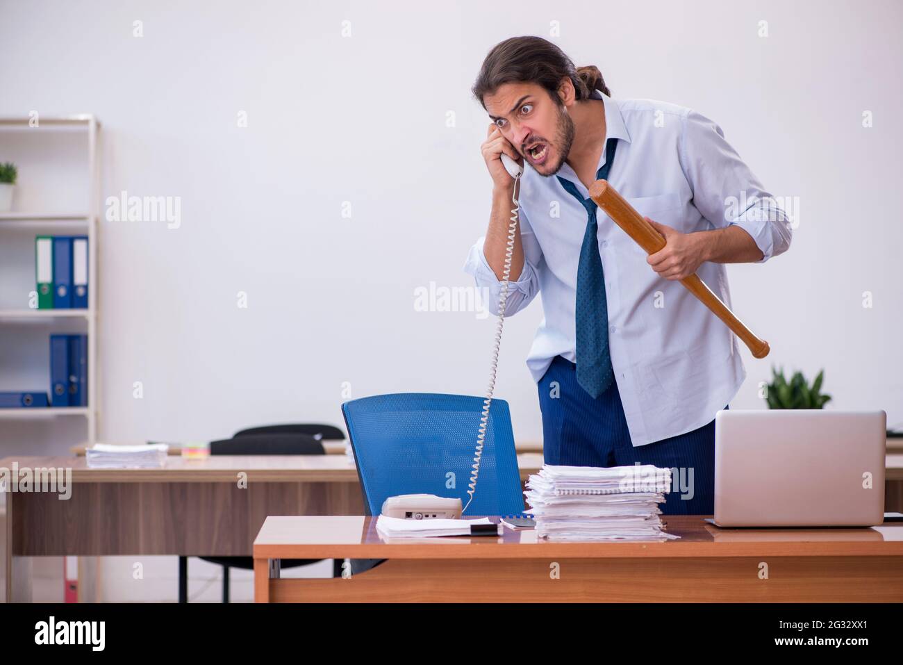 Young furious employee holding baseball bat in the office Stock Photo ...