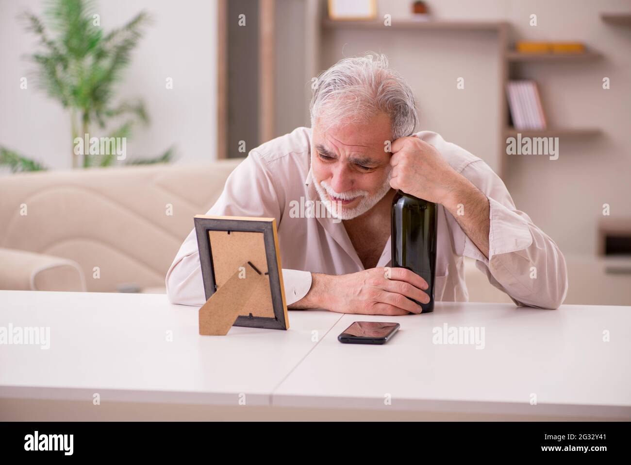 Aged widower drinking alcohol at home Stock Photo - Alamy