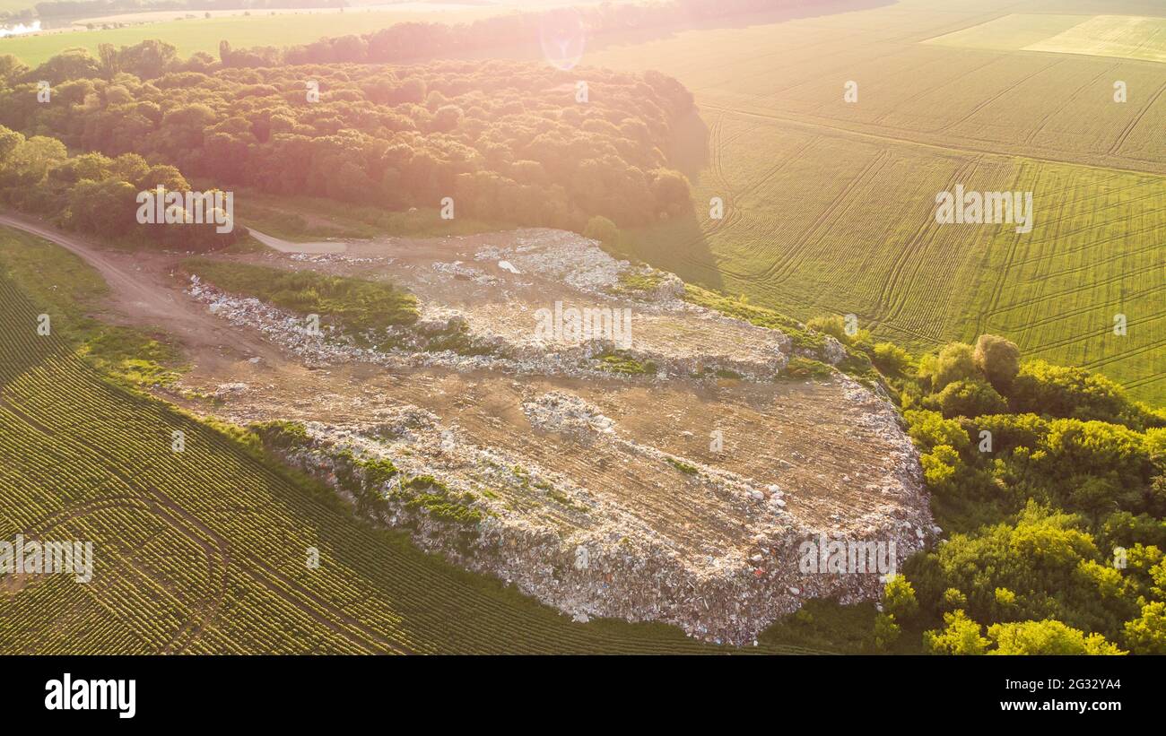 Aerial shot of big rubbish pile lying among field in countryside ...