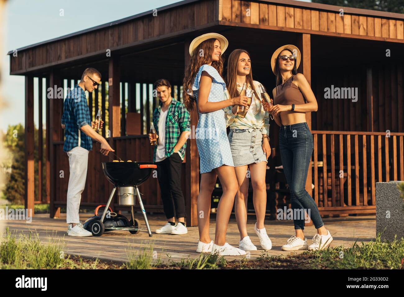Young friends having fun grilling meat while enjoying barbecue, A group ...