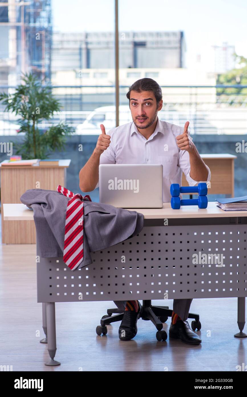 Young employee doing sport exercises at workplace Stock Photo - Alamy