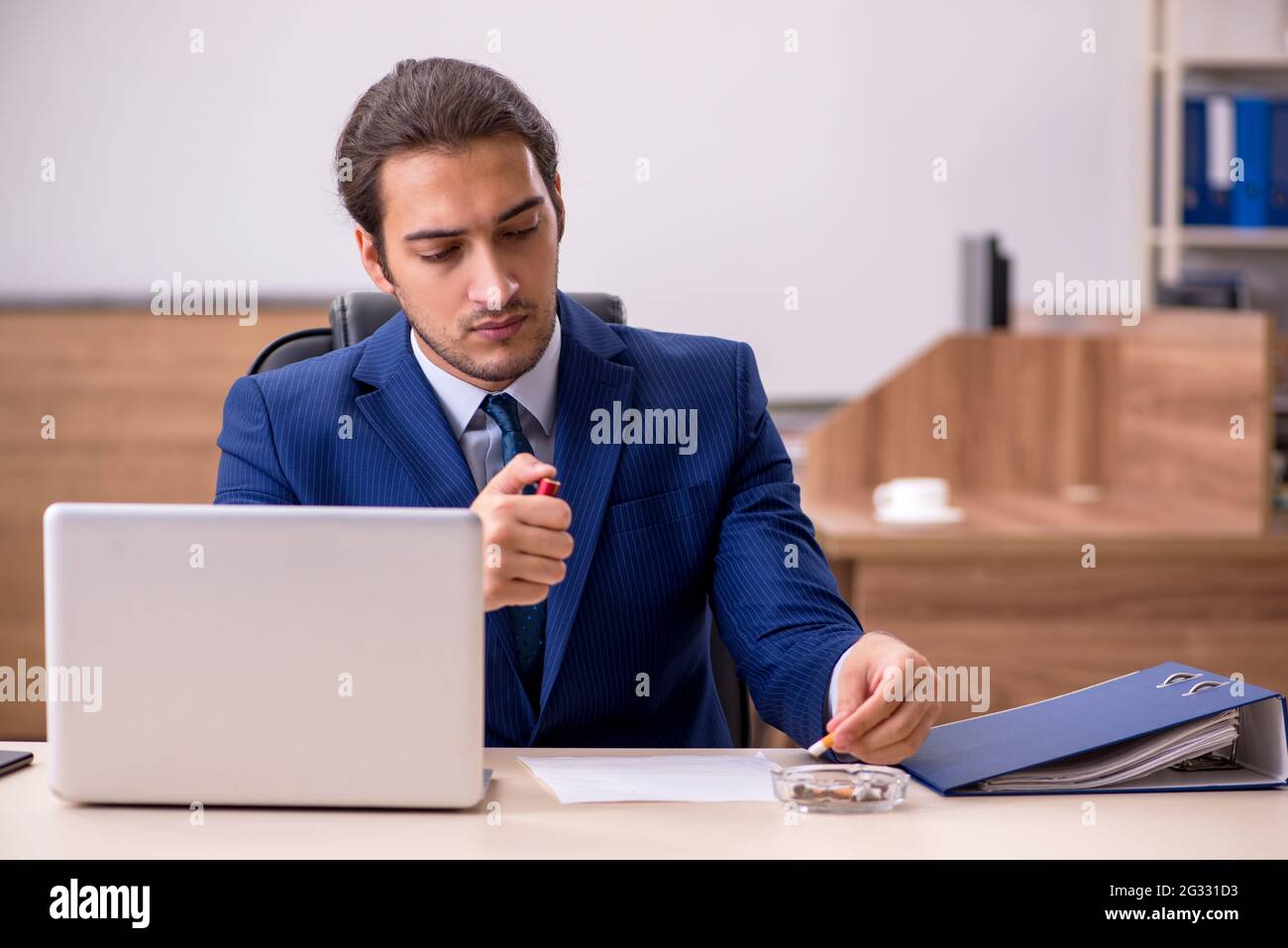 Young man employee smoking cigarettes in the office Stock Photo - Alamy