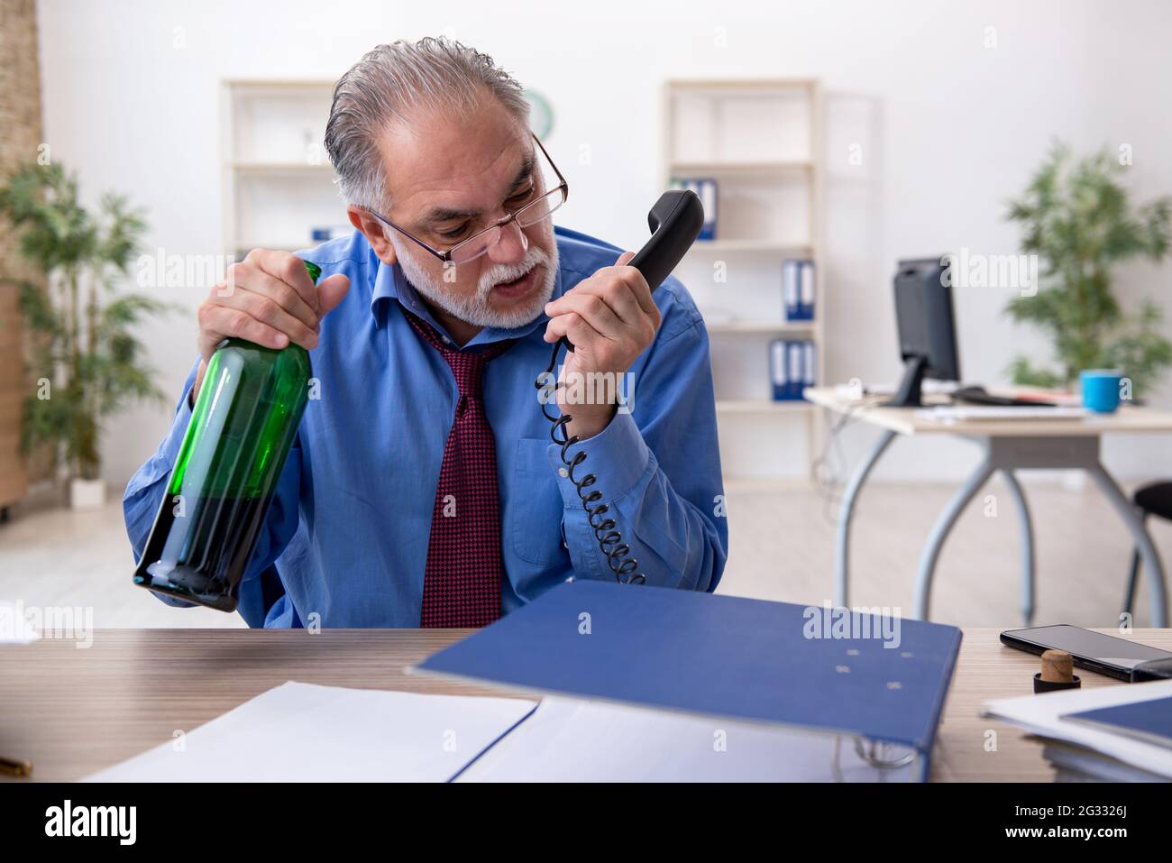 Senior male employee drinking alcohol in the office Stock Photo - Alamy
