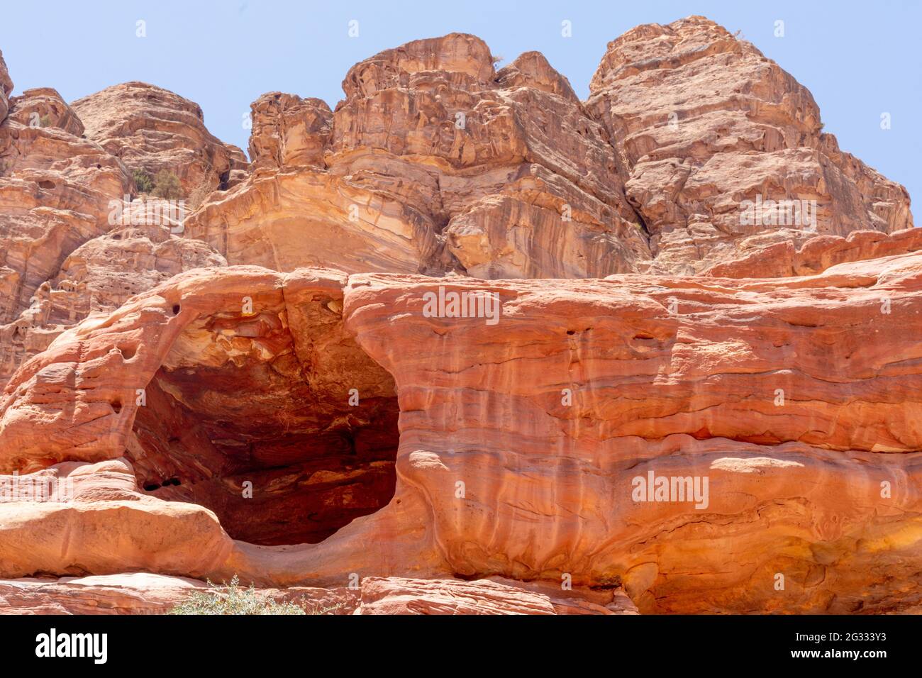Carved cave in multicolored red-rose sandstone with signs of weathering ...