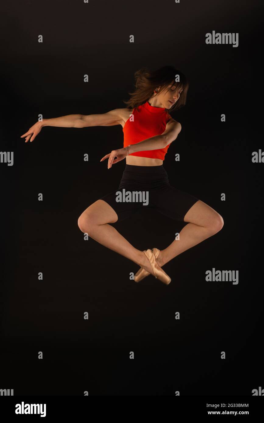 Ballerina is doing a perfect contemporary jump in the air while posing ...