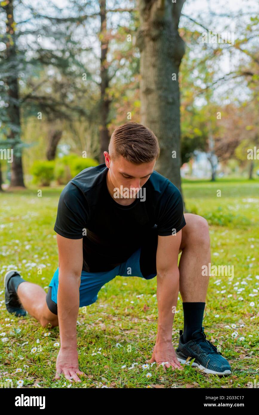 Strong man warming up at city park before jogging. Men stretching for ...