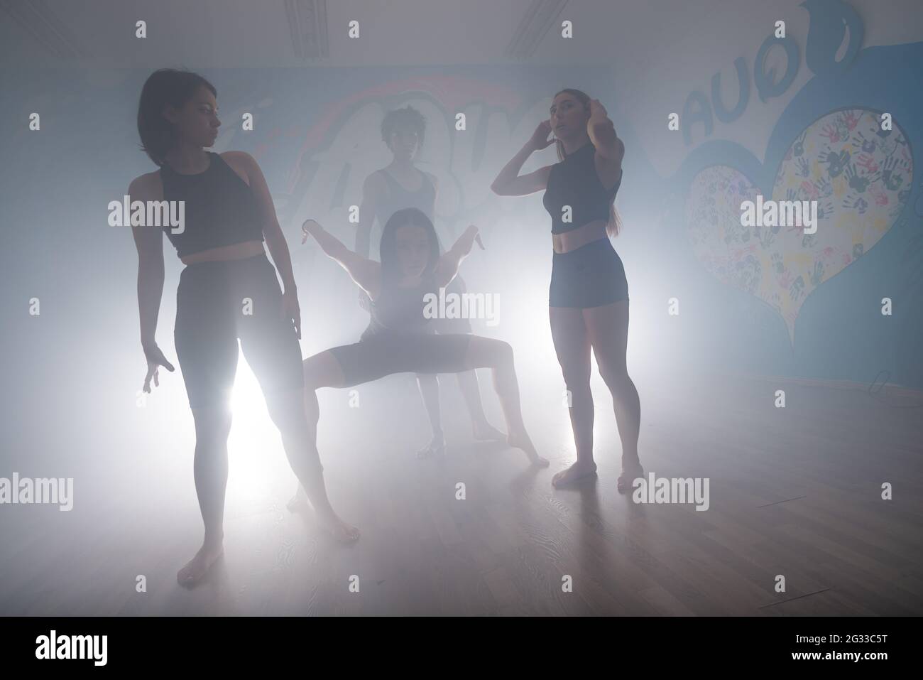Group of multiracial dancers enjoying funky hip hop moves in dark ...