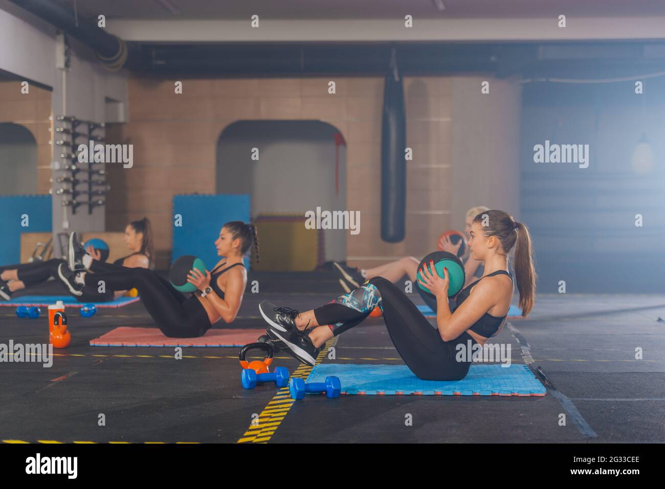 Side view of beautiful young women exercising russian twist with ...