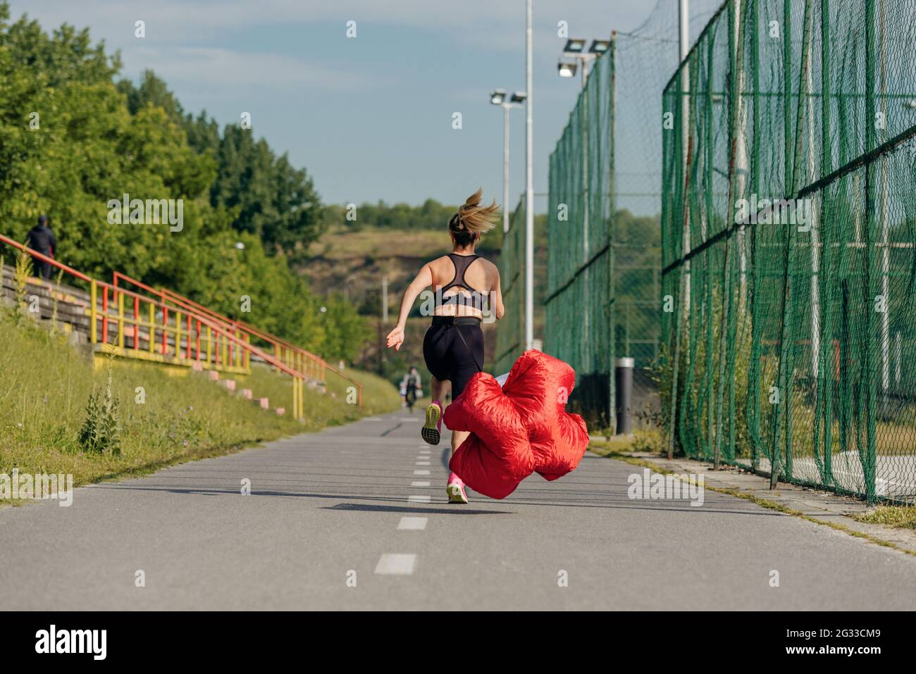 View from the back of a young female athlete running with a parachute ...