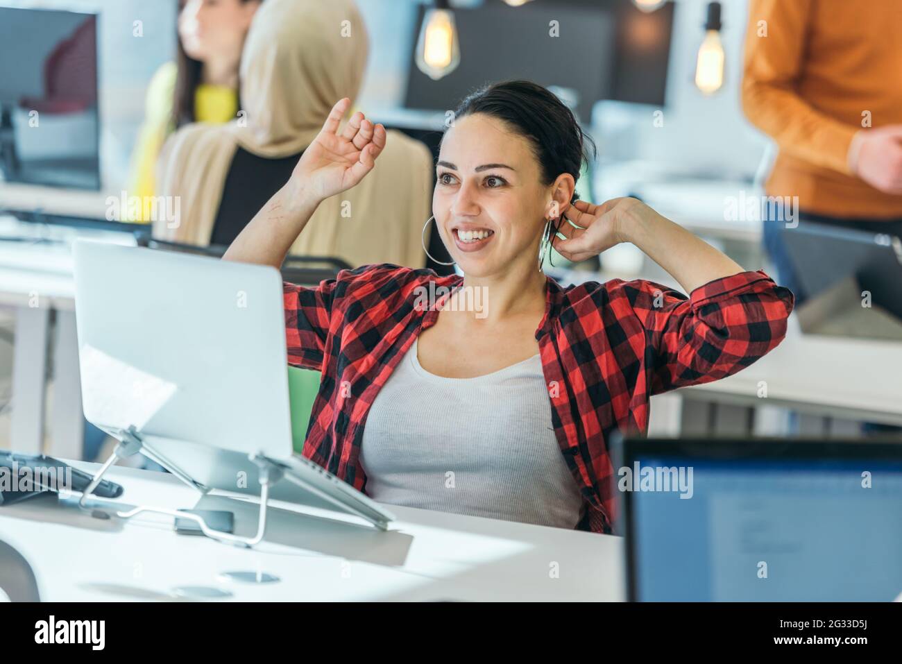 Happy employee cheering while lifting her hands high in the air while ...