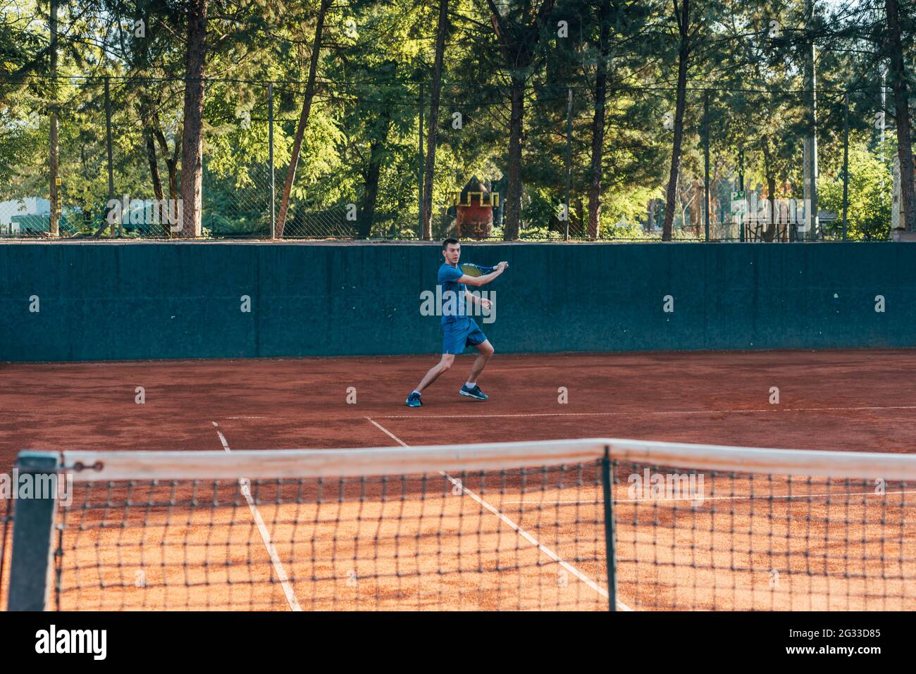 A professional tennis player is serving ball on a clay tennis court ...