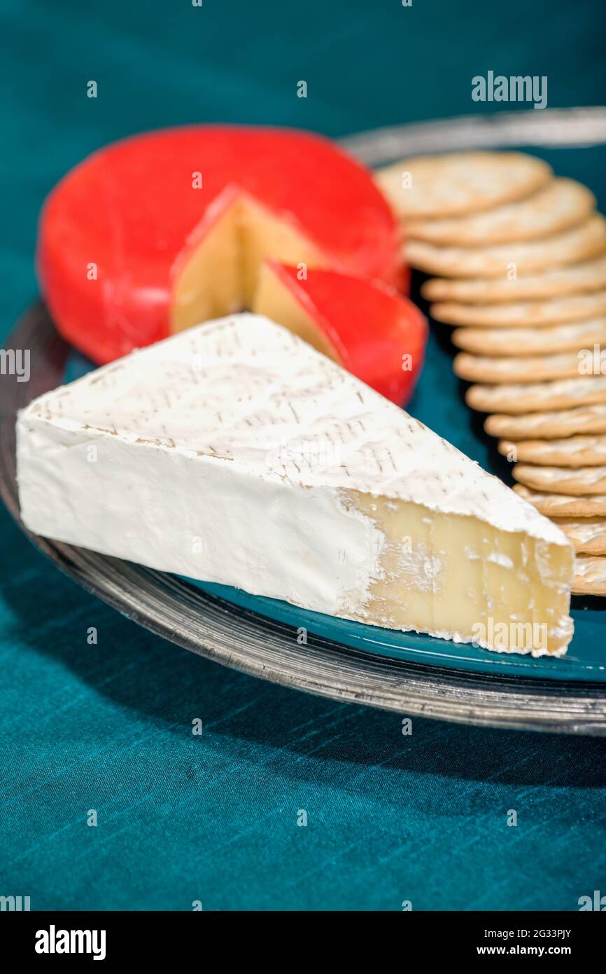 Smoked Baby Brie and Gouda cheese, along with water crackers on plate ...