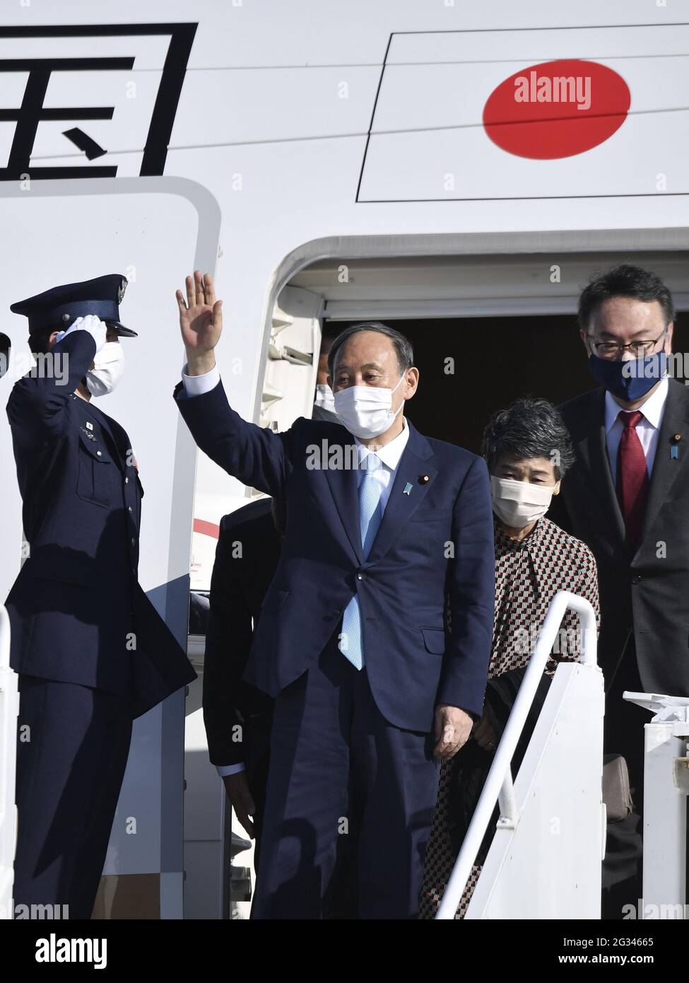 Japanese Prime Minister Yoshihide Suga (C) waves alongside his wife ...