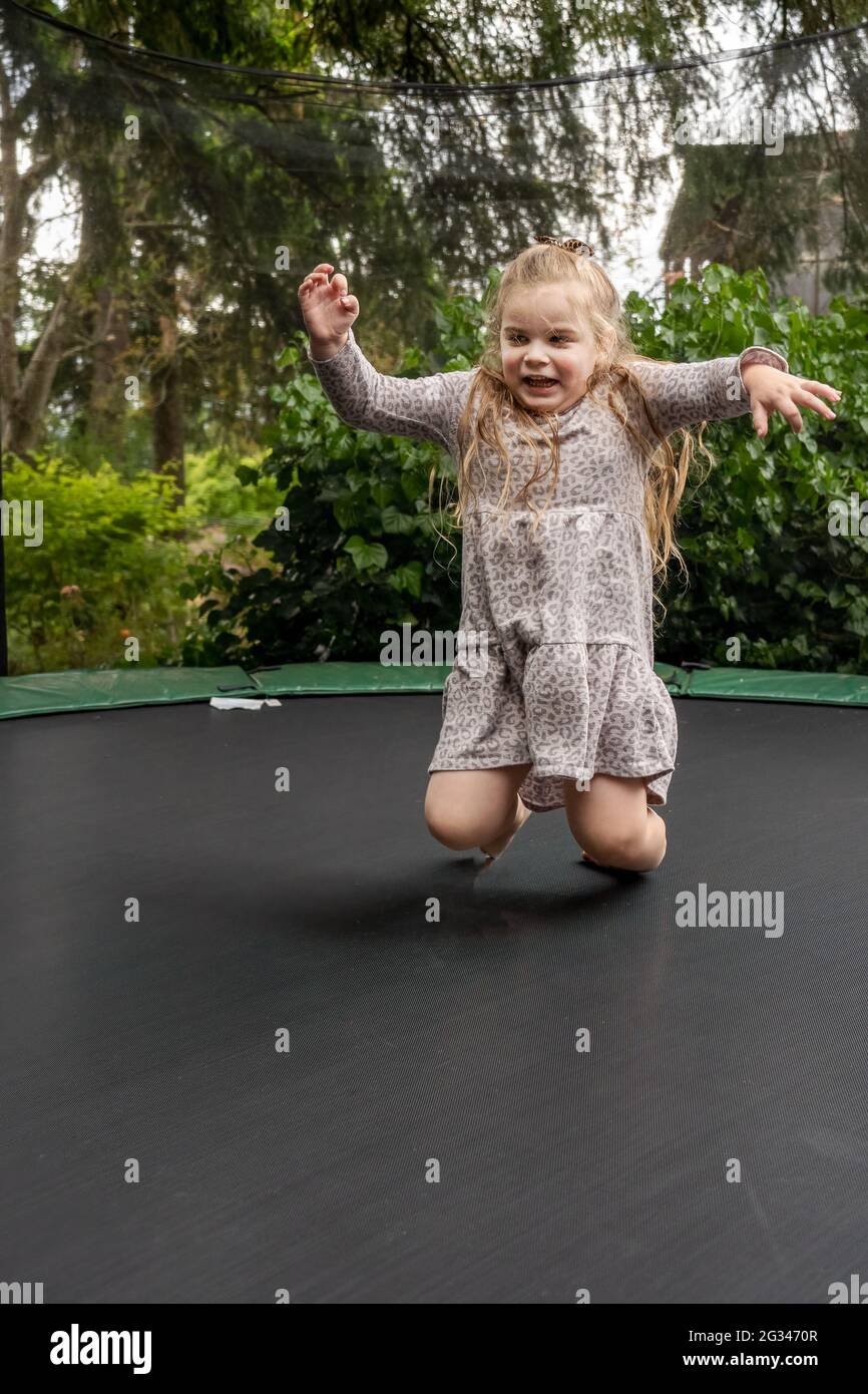Lynwood, Washington, USA. 4 year old girl bouncing down to her knees on ...