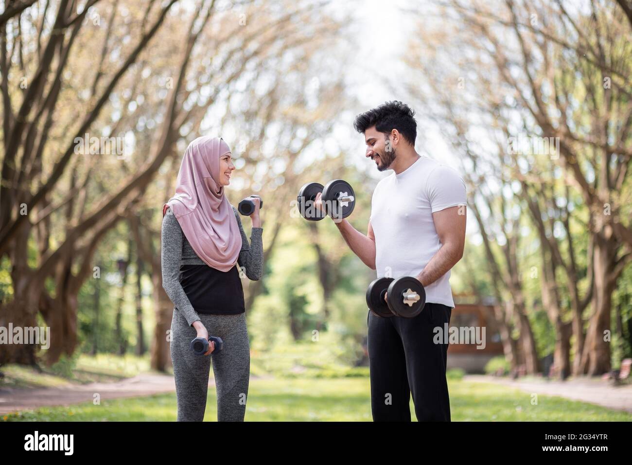 Young woman in hijab and handsome muslim man standing together at green ...