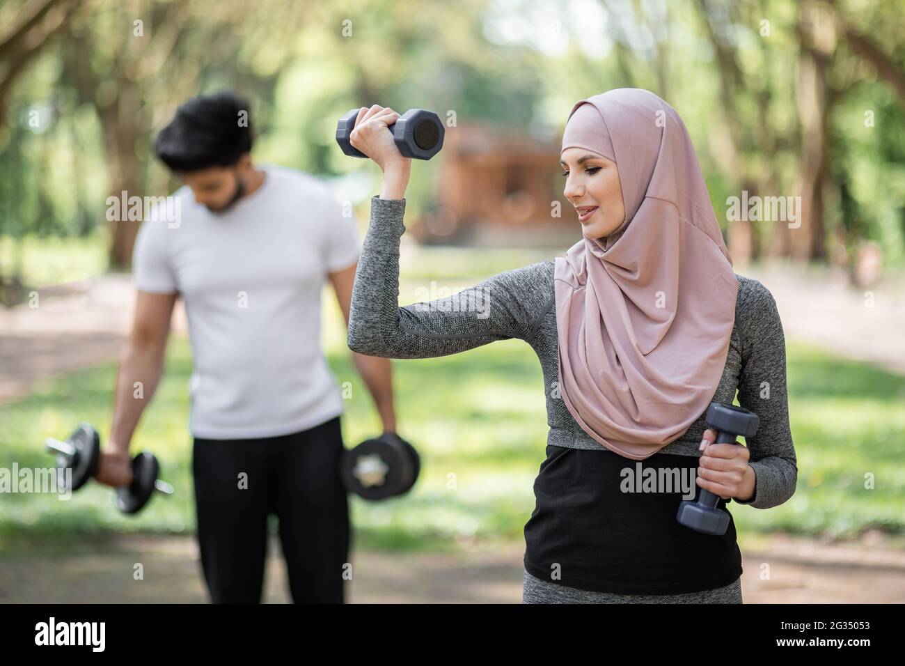 Fit and healthy muslim woman in hijab doing exercises for arms with ...