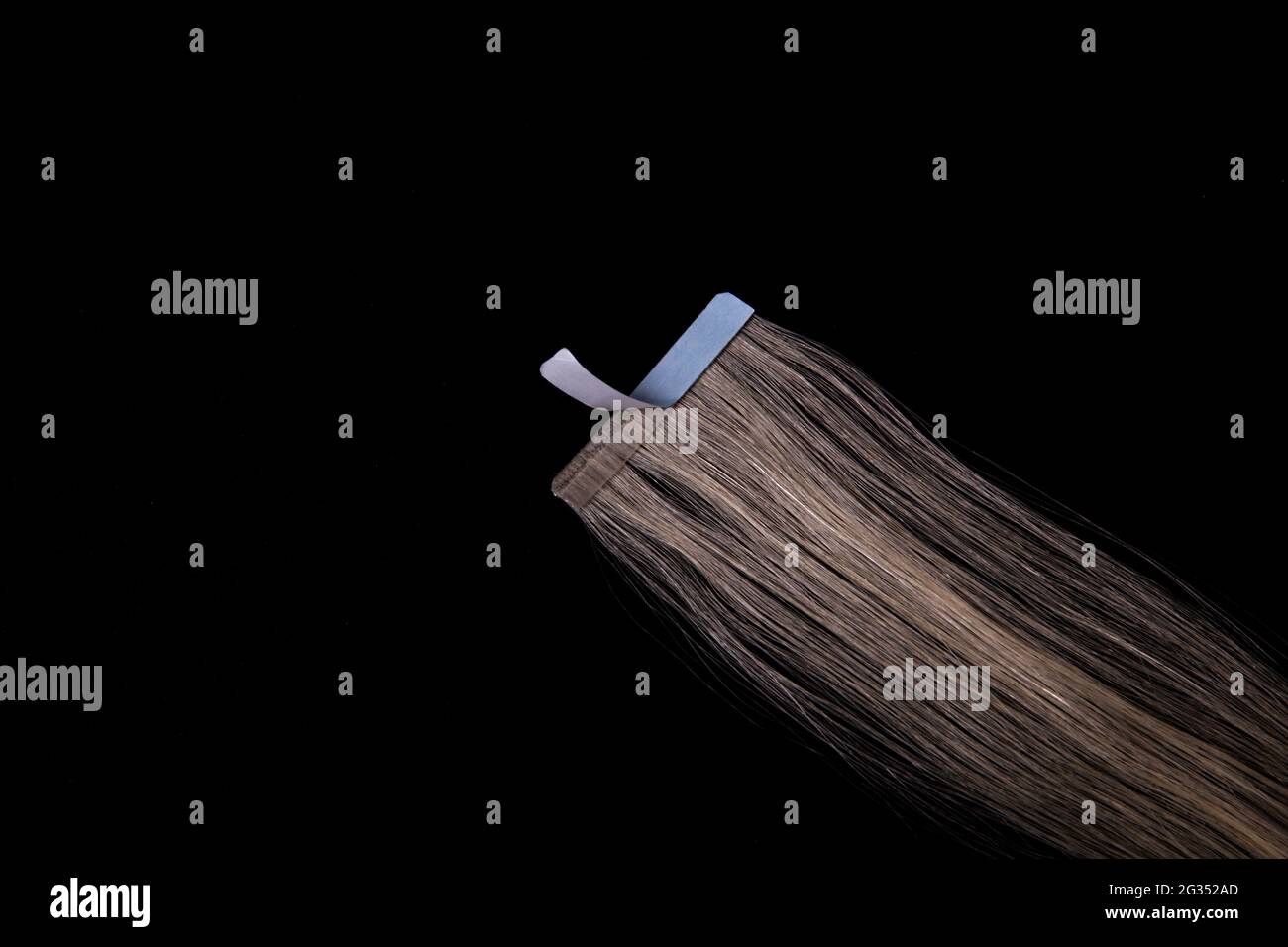 Fake blonde hair on sticky tape on black isolated background. High ...