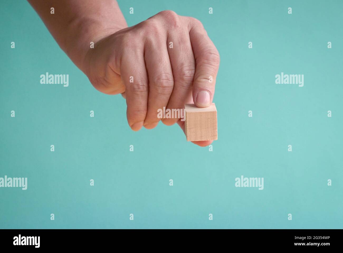 Hand holding a piece of blank wood block. On blue background, copy ...