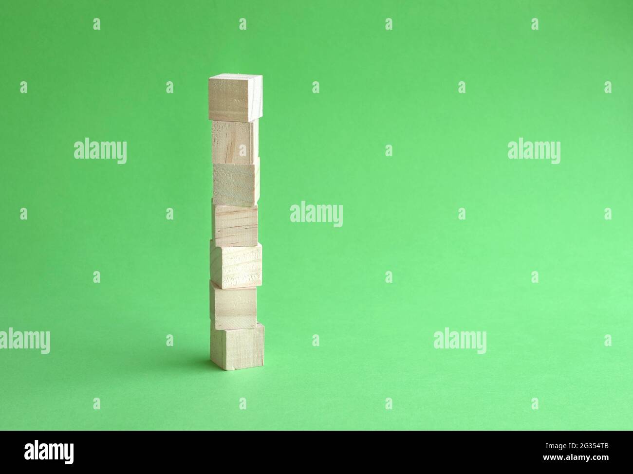 7 letter blank and wood block stacked up, green background. Copy space ...