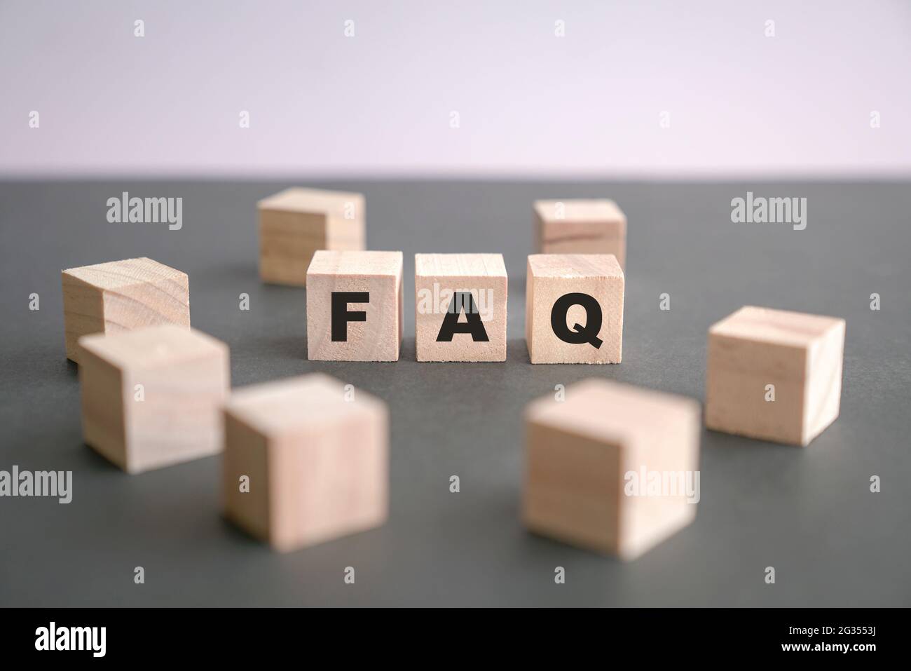 FAQ written on wooden blocks on dark grey background. Frequently Ask ...