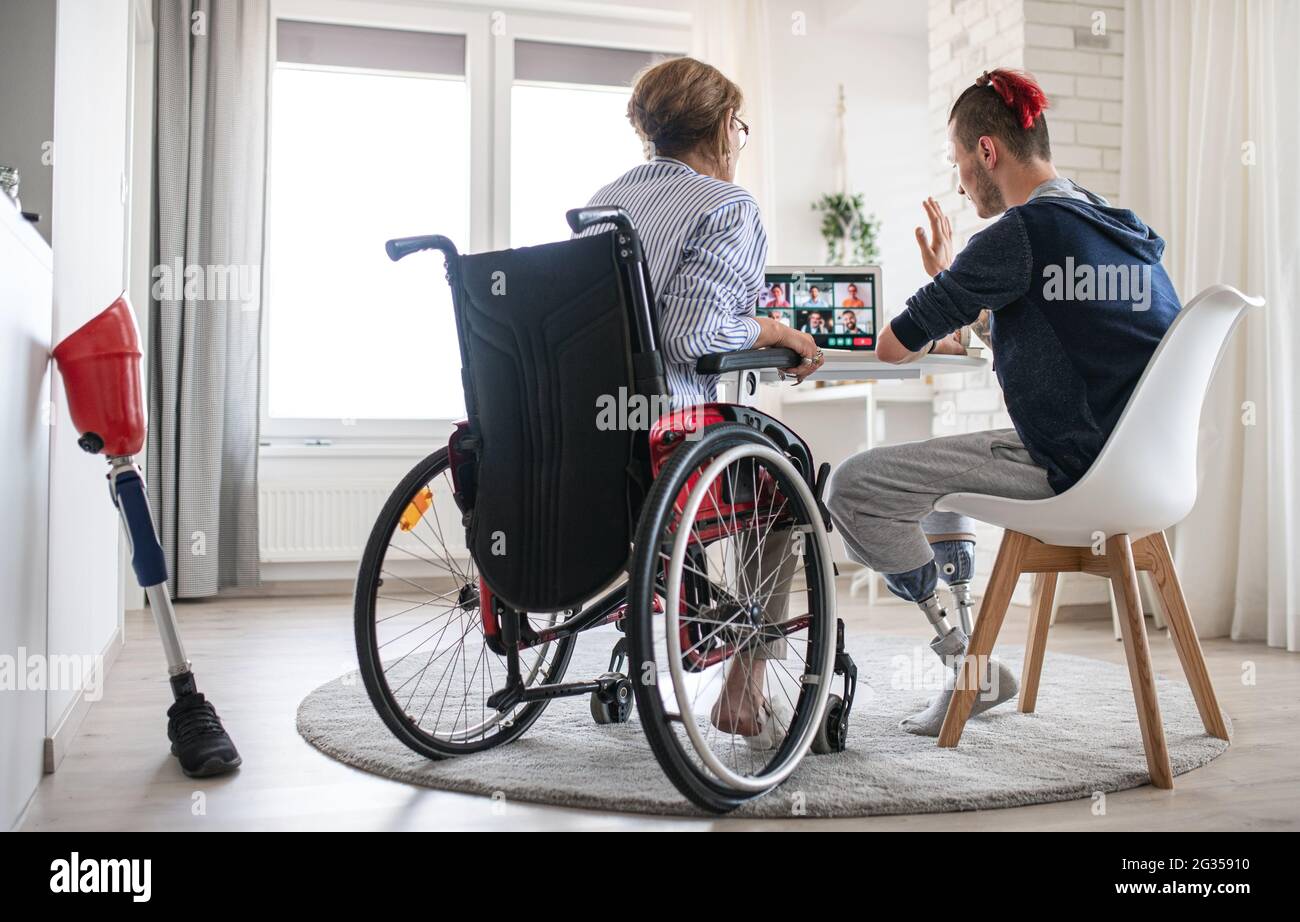 Rear view of disabled people sitting at the table indoors at home ...