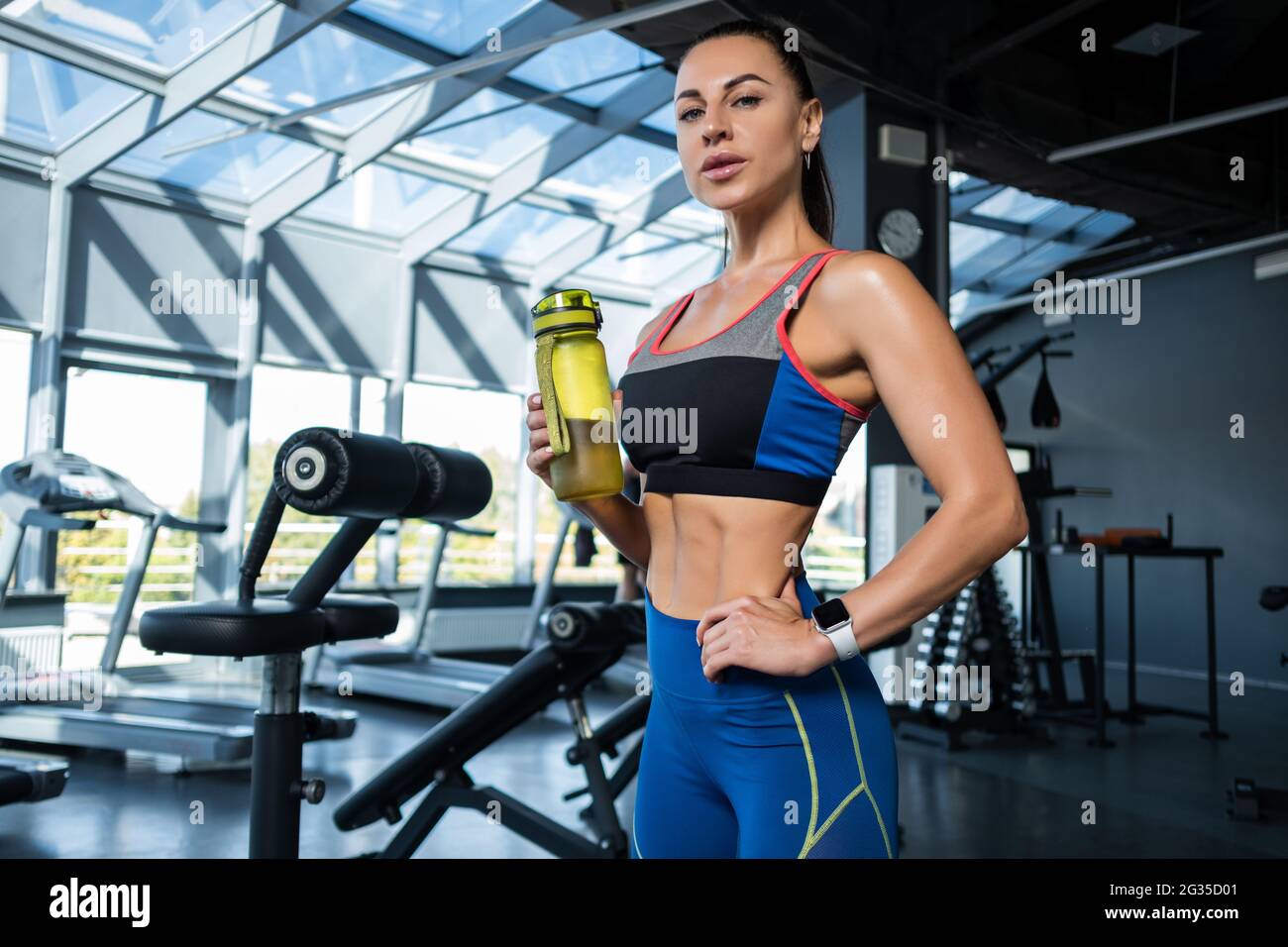 Sporty girl standing in gym with water bottle Stock Photo - Alamy