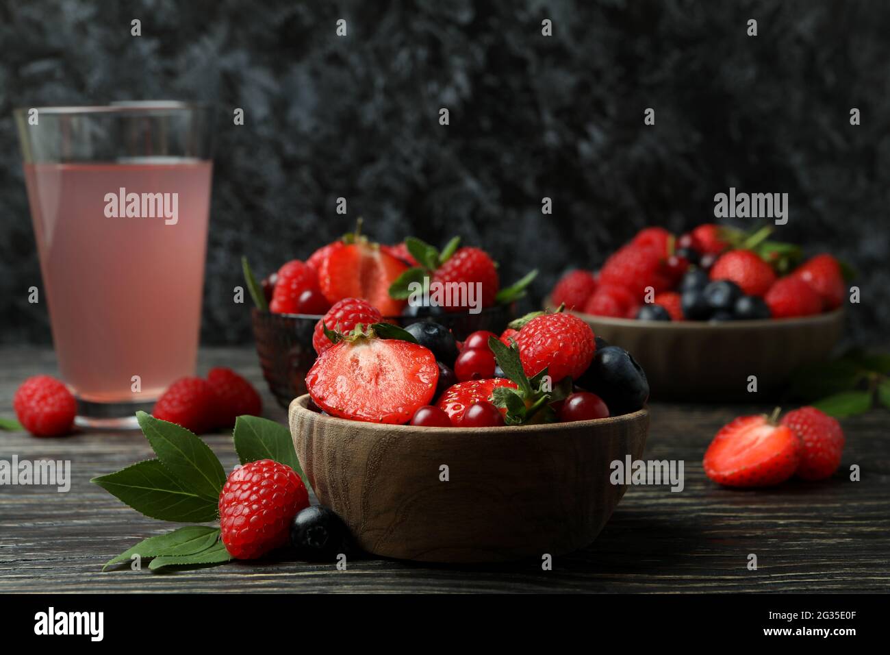 Bowls with berry mix and juice on wooden table Stock Photo - Alamy