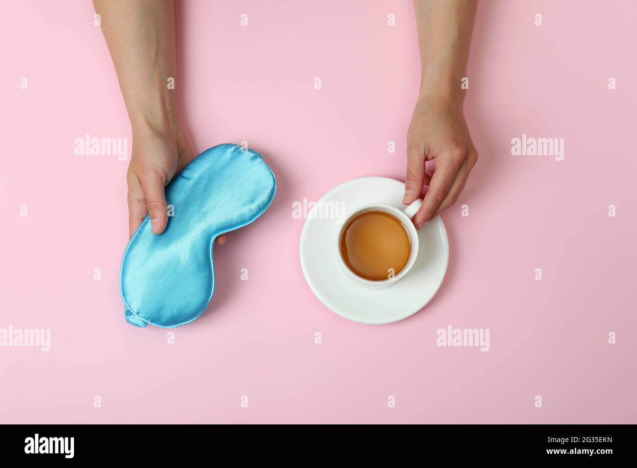 Female hands hold sleep mask and tea on pink background Stock Photo - Alamy