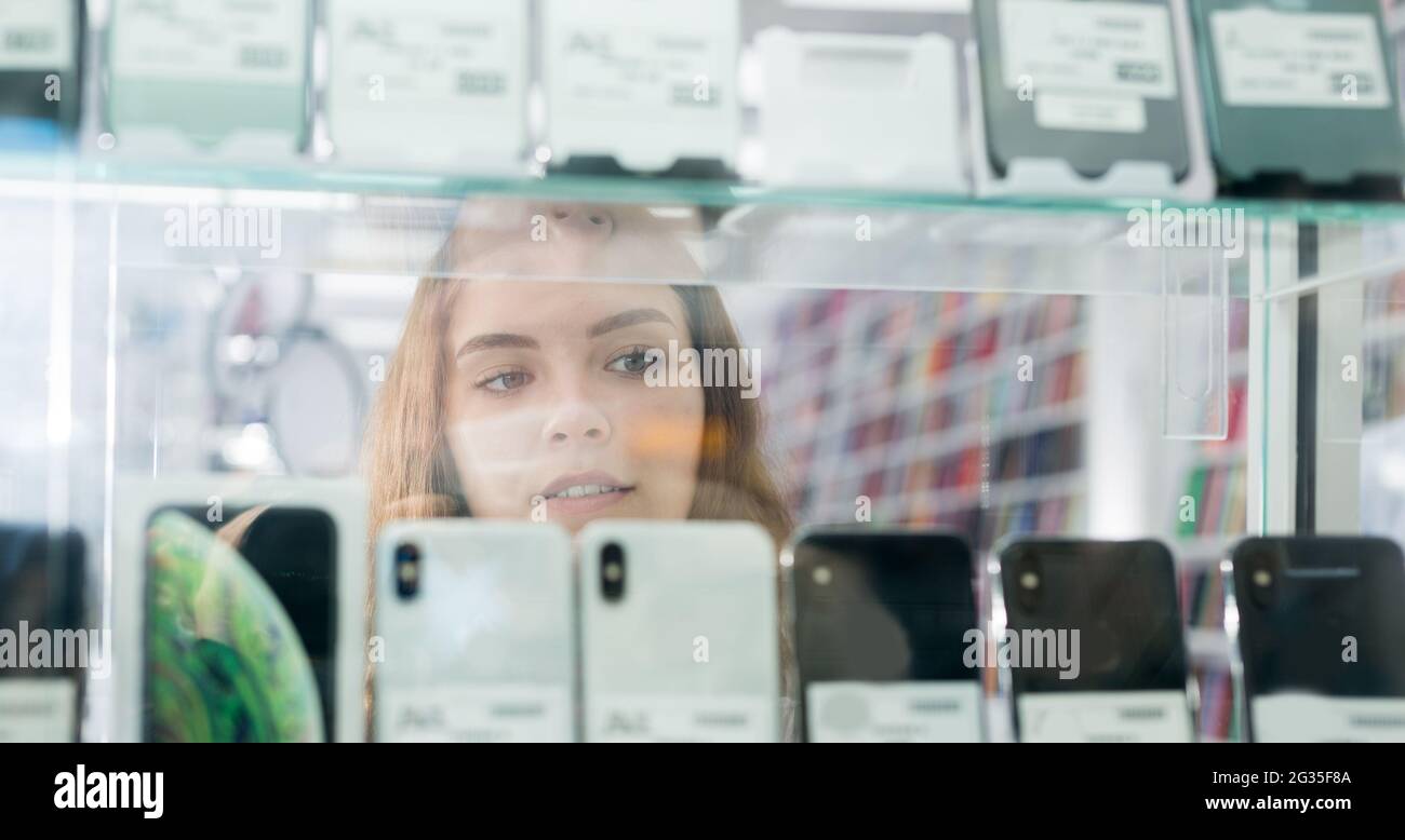 Girl looks at the shop window with mobile phones Stock Photo - Alamy